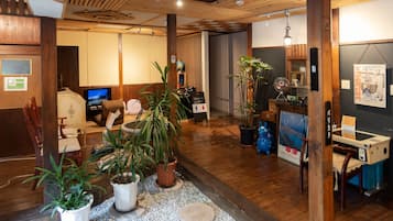 Um quarto tradicional em estilo japonês, com tatames, uma televisão e diversas plantas.
