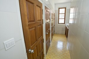 Um corredor com portas de madeira, ch ão de azulejos e uma janela.