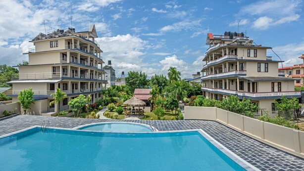 Um hotel com piscina, várias varandas e vegetação exuberante.