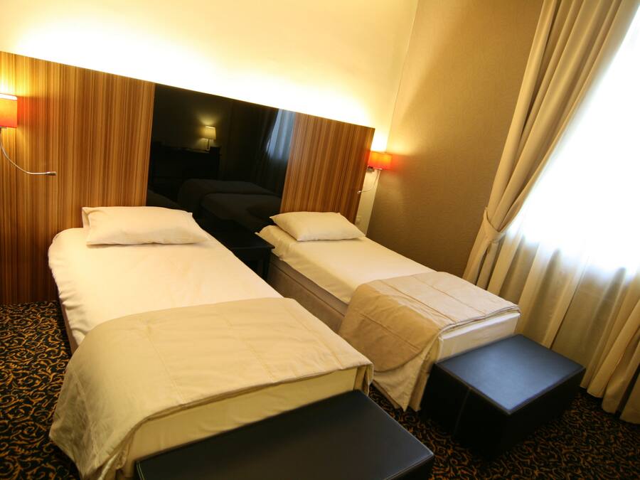 Quarto de hotel com duas camas de solteiro, uma secretária pequena e uma cadeira.