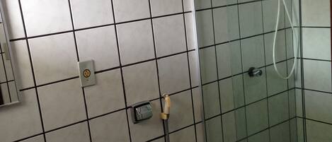 Casa de banho com lavatório, sanita e cabine de duche com parede de vidro.