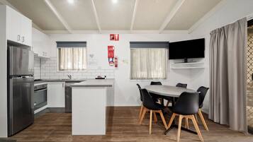 Cozinha moderna com ilha central, área de jantar com mesa e cadeiras, e televisão de tela plana montada acima da ilha.