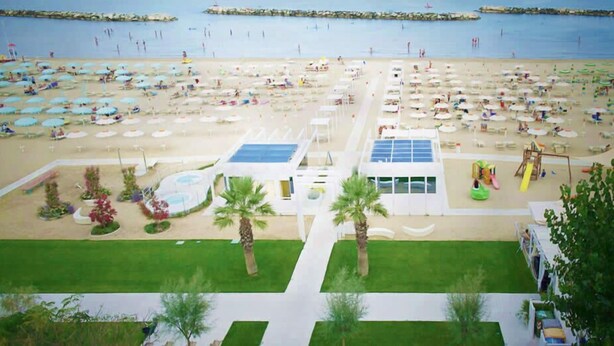 Um resort à beira-mar com vários espreguiçadeiras, um espaço de recreação infantil e uma piscina.