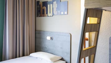 Uma cama com cabeceira de madeira, um travesseiro branco e uma parede com uma placa que diz 'chut...'.