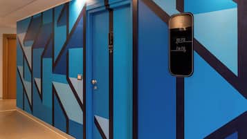 Um elevador moderno com visor digital exibindo os números dos andares e um design geométrico azul na parede.