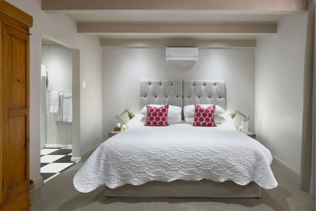 Quarto bem arrumado com uma cama grande, cabeceira e duas mesas de cabeceira com abajures.