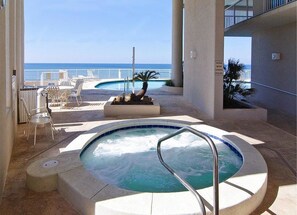 Uma área de piscina com hidromassagem, espreguiçadeiras e vista para o mar.