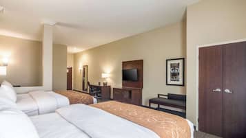 Quarto de hotel com duas camas, uma escrivaninha, uma TV e um guarda-roupa.