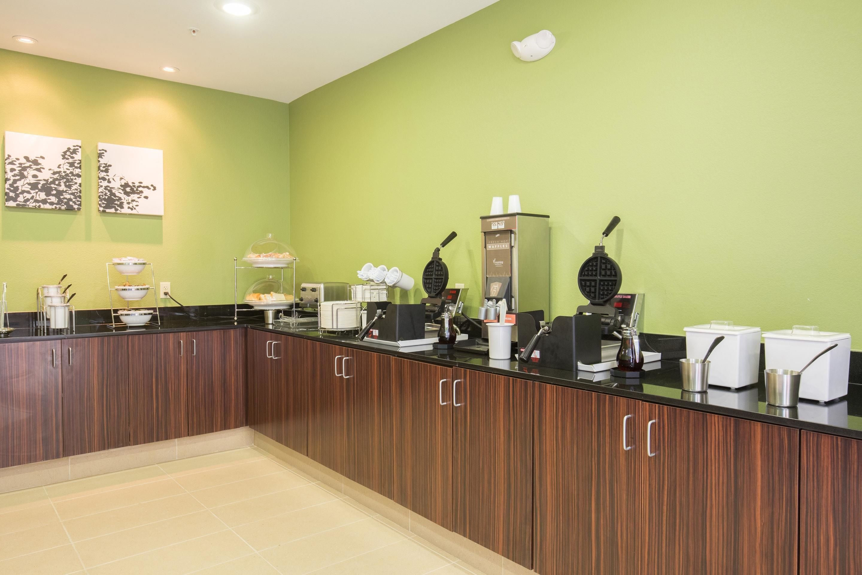 Uma cozinha moderna com bancada de madeira, máquinas de café e um aparelho para waffles.