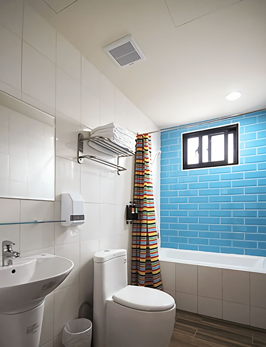 Casa de banho com lavatório branco, sanita e zona de duche revestida a azulejos azuis.