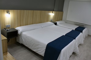 Quarto de hotel com cama grande, mesas de cabeceira e luminária fixada na parede.