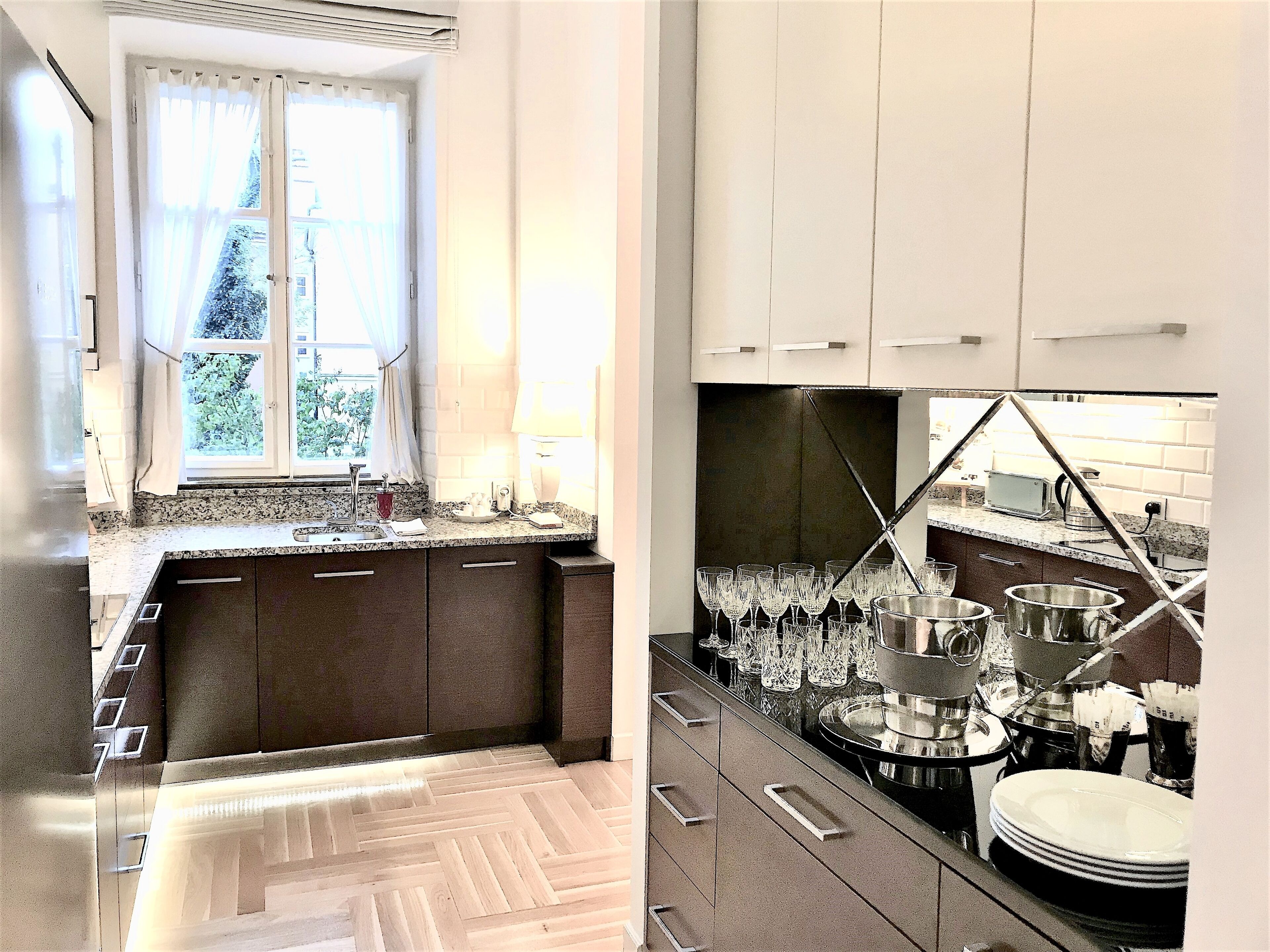 Uma cozinha moderna com piso em padrão herringbone, uma janela com cortinas e uma pia com torneira.