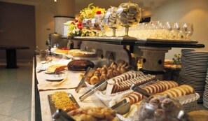 Buffet com diversos doces e pastelaria, incluindo bolos, tortas e tarteletes de fruta.