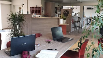 Uma área de jantar moderna com dois laptops, um caderno e uma caneta sobre uma mesa de madeira.