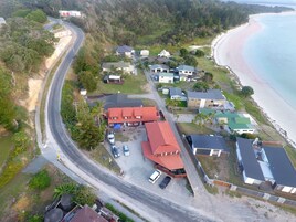Vista aérea de uma área residencial costeira com casas, uma estrada e uma praia.
