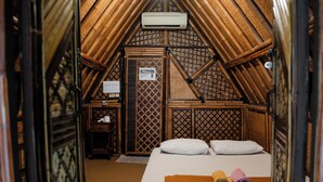 Um quarto aconchegante com telhado triangular, cama, almofadas e toalhas.