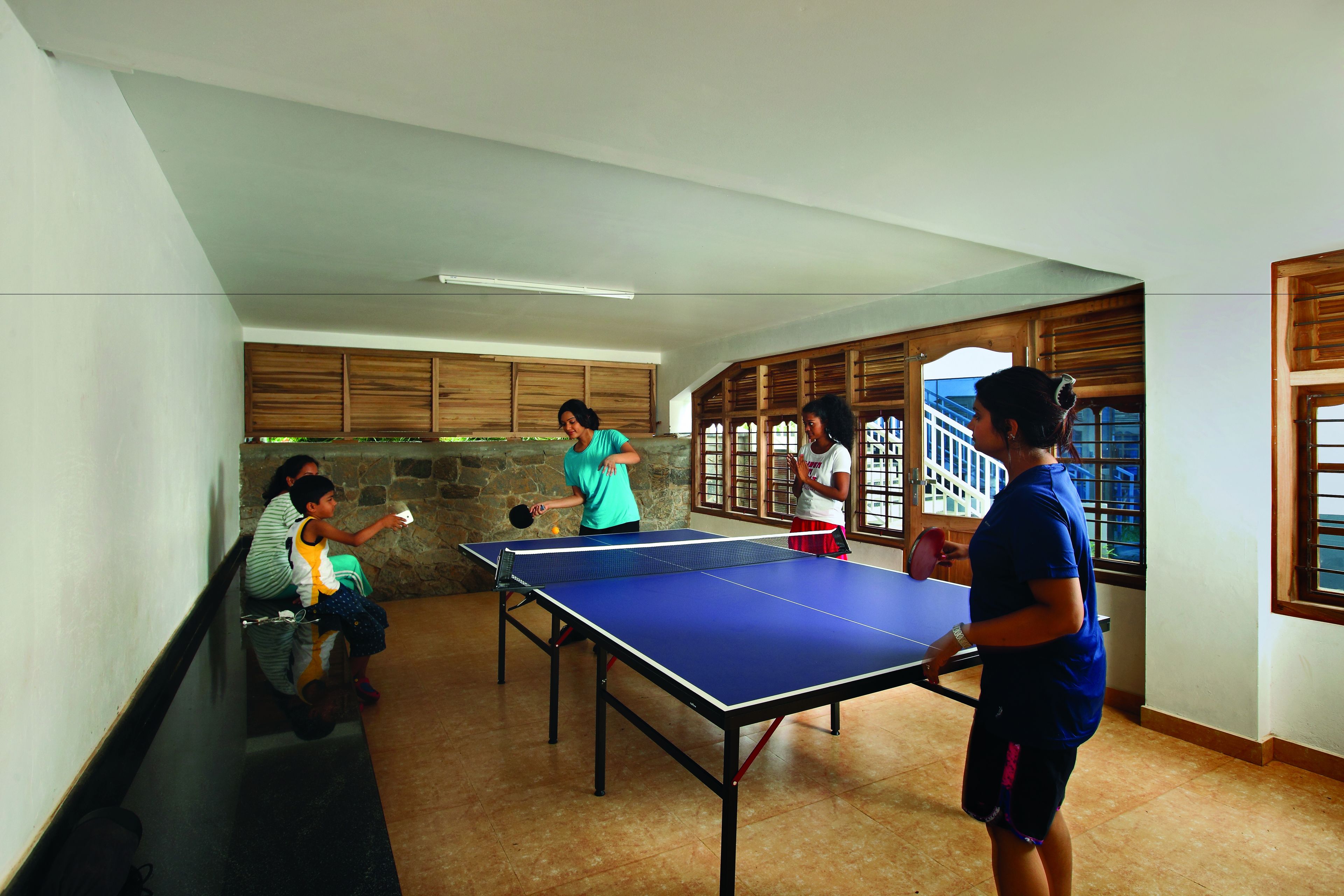 Quarto com mesa de pingue-pongue, paredes de pedra e armários de madeira.