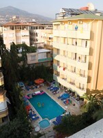 Um edifício com vários andares e uma área de piscina no terraço, incluindo espreguiçadeiras e guarda-sóis.