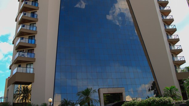 Um edifício alto com design angular característico, com várias varandas e fachada de vidro refletivo.