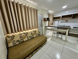 Uma sala de estar moderna com sofá, mesa de jantar e cozinha equipada com frigorífico e armários.