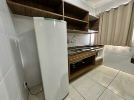 Uma cozinha compacta com geladeira embutida, pia e prateleiras de madeira.