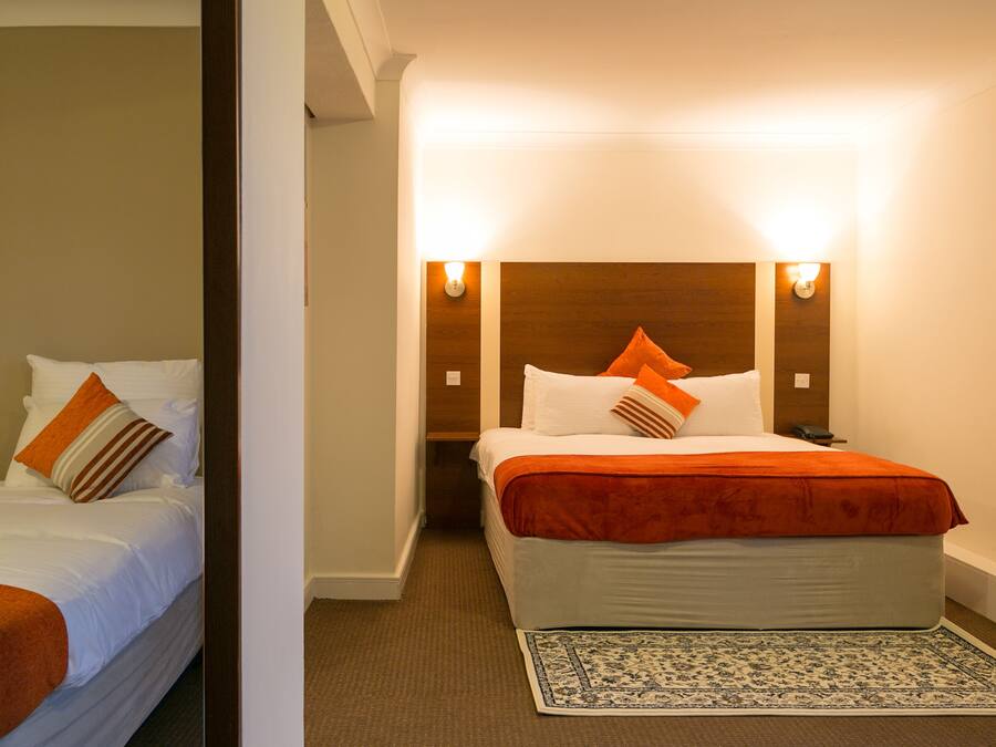 Quarto de hotel com duas camas, cabeceira de madeira e um tapete estampado.