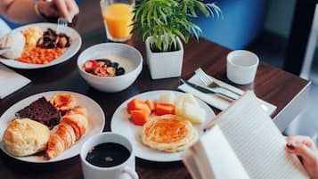 Uma mesa de café da manhã com pratos de comida, uma xícara de café e um livro.