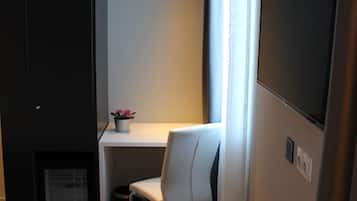 Quarto de hotel com cama, escrivaninha, cadeira, televisão e carpete com padrão de estrelas.
