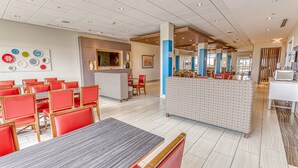 Um restaurante espaçoso com cabines estofadas em vermelho e um balcão central.