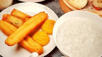 Uma mesa com diversos pratos, incluindo comidas fritas, um recipiente com arroz e alguns acompanhamentos.