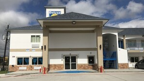 Entrada de um hotel com uma placa indicando 'Deluxe Inn Baytown'.