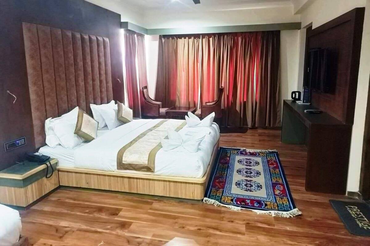 Quarto de hotel com cama grande, escrivaninha, cadeira, televisão e ventoinha de teto.