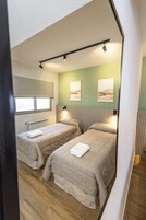 Quarto com duas camas, um radiador e obras de arte nas paredes.
