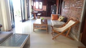 Uma sala de estar ampla, com sofá, mesa de centro e poltrona acolchoada.