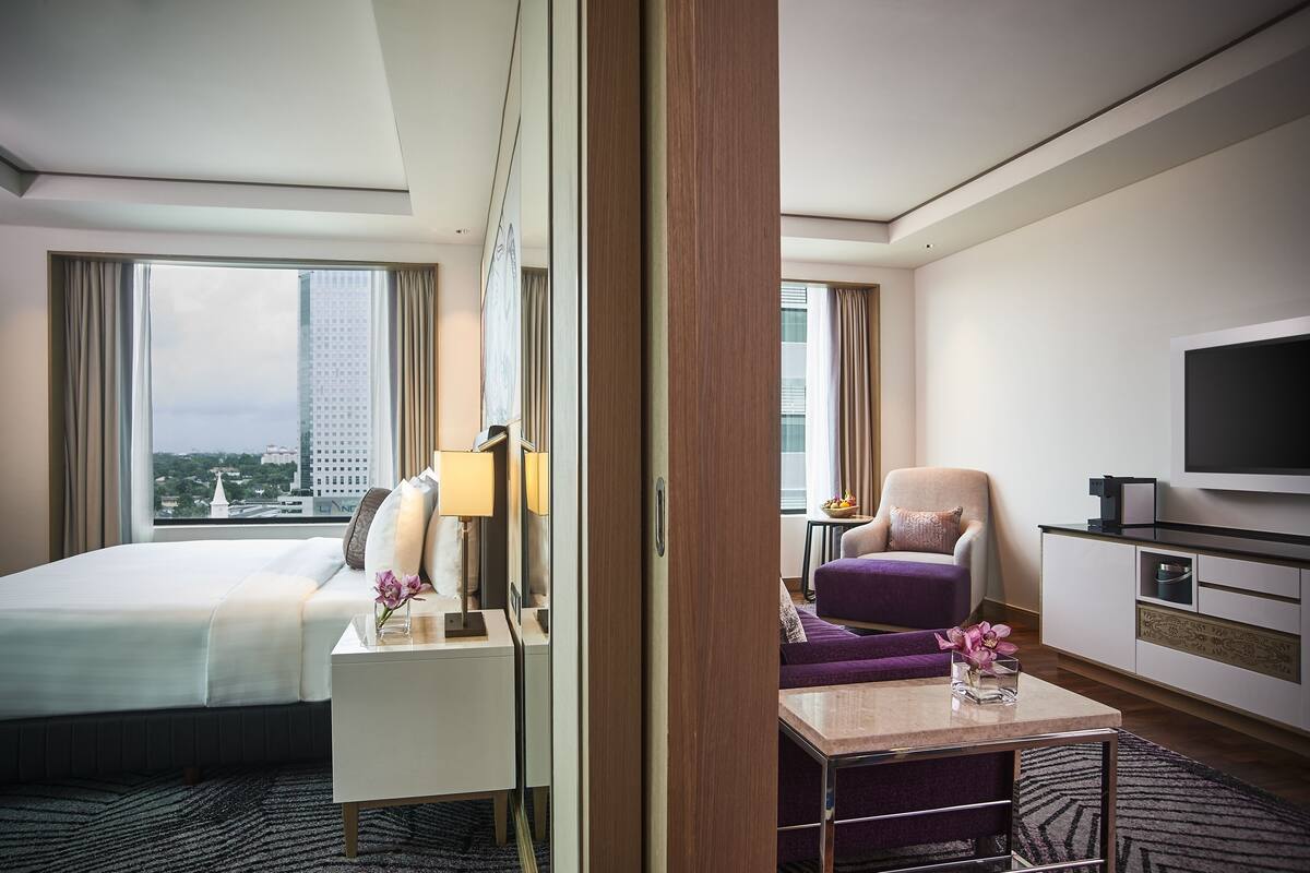 Quarto de hotel com cama, escrivaninha, cadeira, televisão e vista para a cidade.