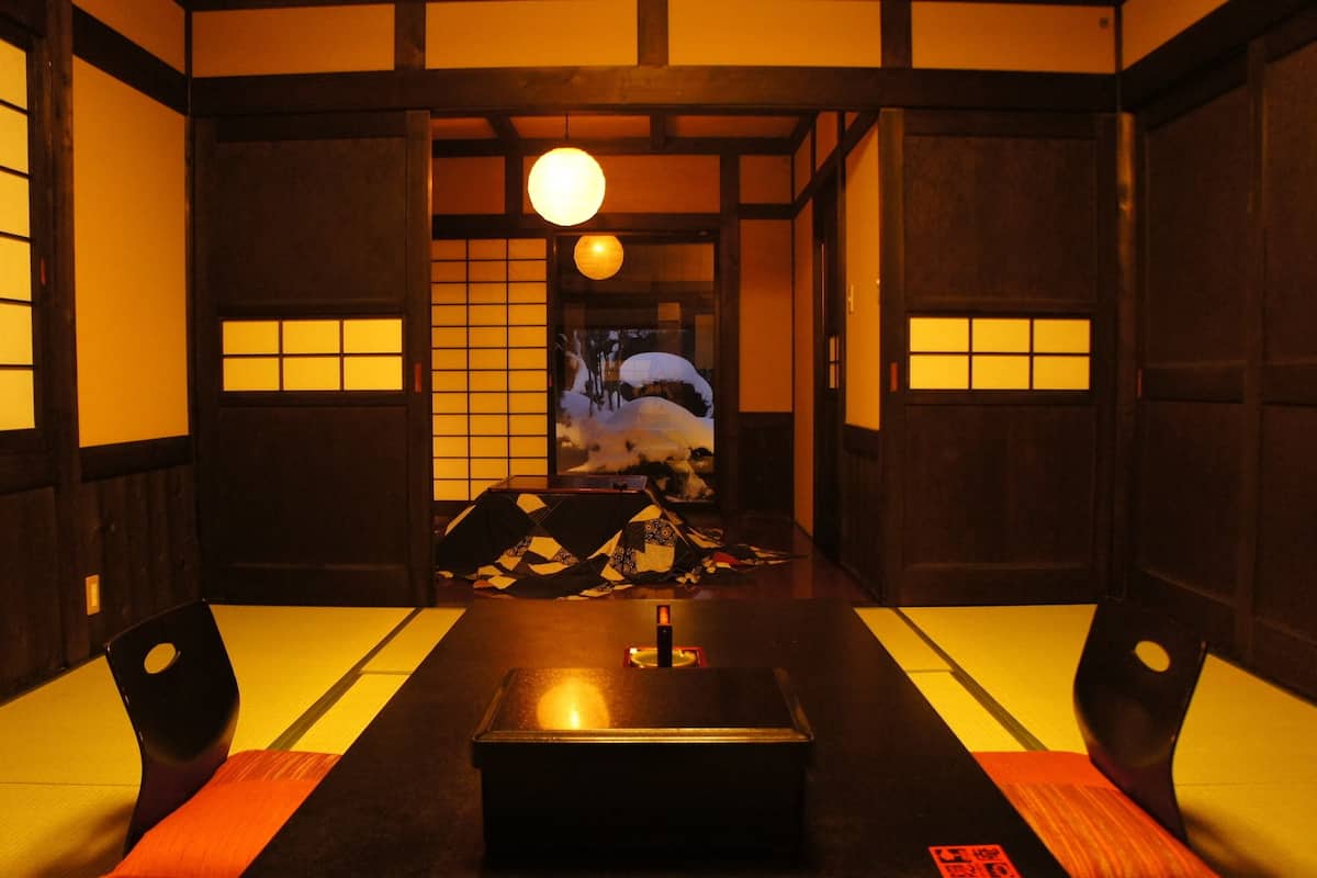 Um quarto japonês tradicional com tatames, uma mesa baixa e portas deslizantes.