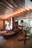 Academia moderna com equipamentos de ginástica, um visor digital e uma parede de vidro.