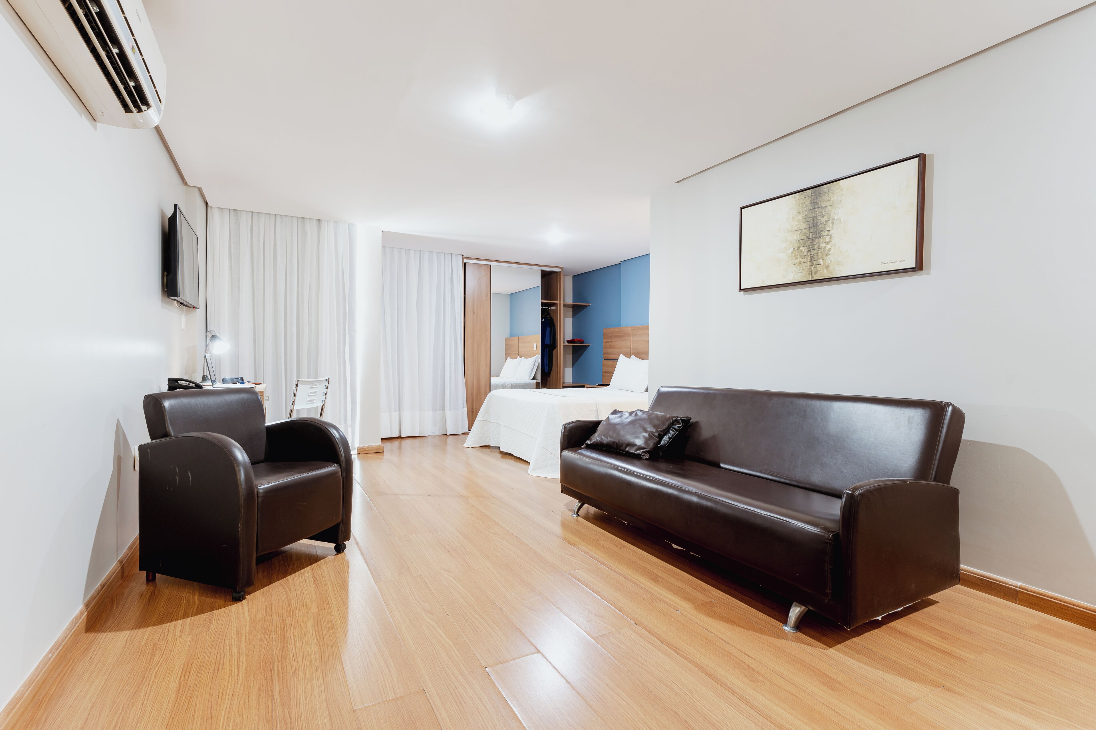 Quarto de hotel com cama, sofá, escrivaninha e cadeira.