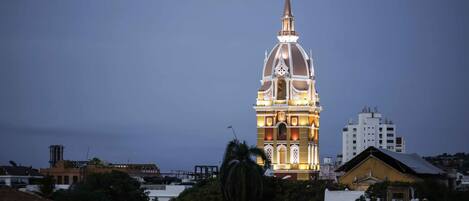 Um edifício histórico com uma torre e cúpula imponentes, rodeado por outros edifícios e palmeiras.