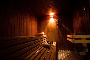 Uma sauna de madeira com bancos e um banco com uma toalha e um recipiente de metal.