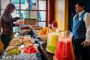 Buffet com diversos alimentos e bebidas, incluindo frutas, saladas e uma jarra de refrescos.