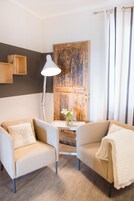 Uma sala de estar moderna com dois sofás, uma porta de madeira, uma pequena mesa com um vaso e um abajur.