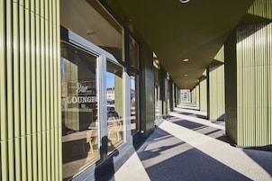 Um corredor com design moderno, com uma área de bar/lounge visível pelas janelas.