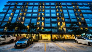 Hotel com vários andares, fachada moderna, janelas iluminadas e entrada bem iluminada.