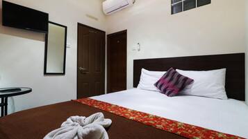 Quarto de hotel com uma cama, televisão na parede, ar condicionado e uma porta.