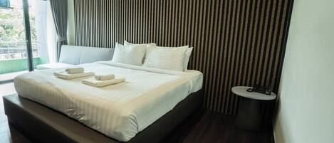 Quarto de hotel moderno com uma cama grande, mesa de cabeceira e vista para o exterior.