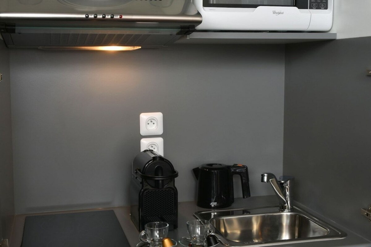 Uma cozinha compacta com micro-ondas, cafeteira e pia.