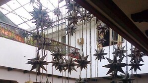 Um átrio de vários níveis com decorações em formato de estrela suspensas e plantas em vasos.