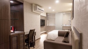 Quarto de hotel moderno com escrivaninha de madeira, sofá confortável, cama e um espelho grande.