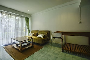 Uma sala de estar com sofá, mesa de centro, poltrona e uma mesinha.